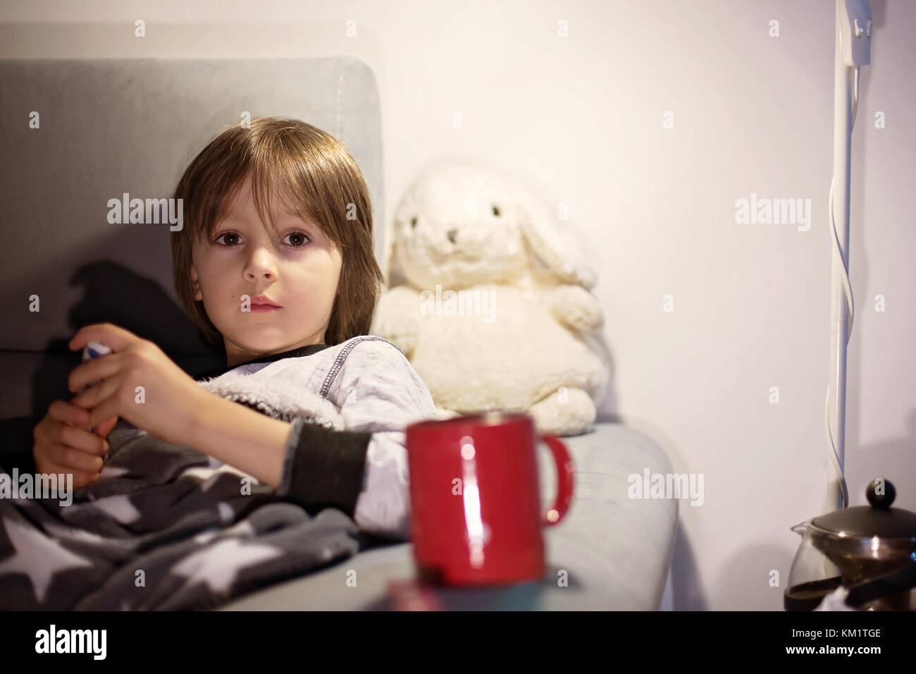 Sick child boy lying on the sofa with a fever, resting at home Stock ...