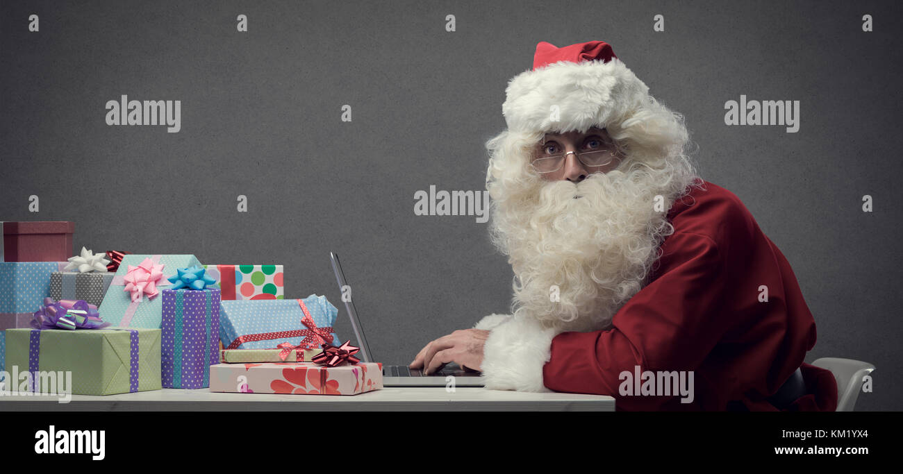 Santa Claus connecting and working online with his laptop, he is ...