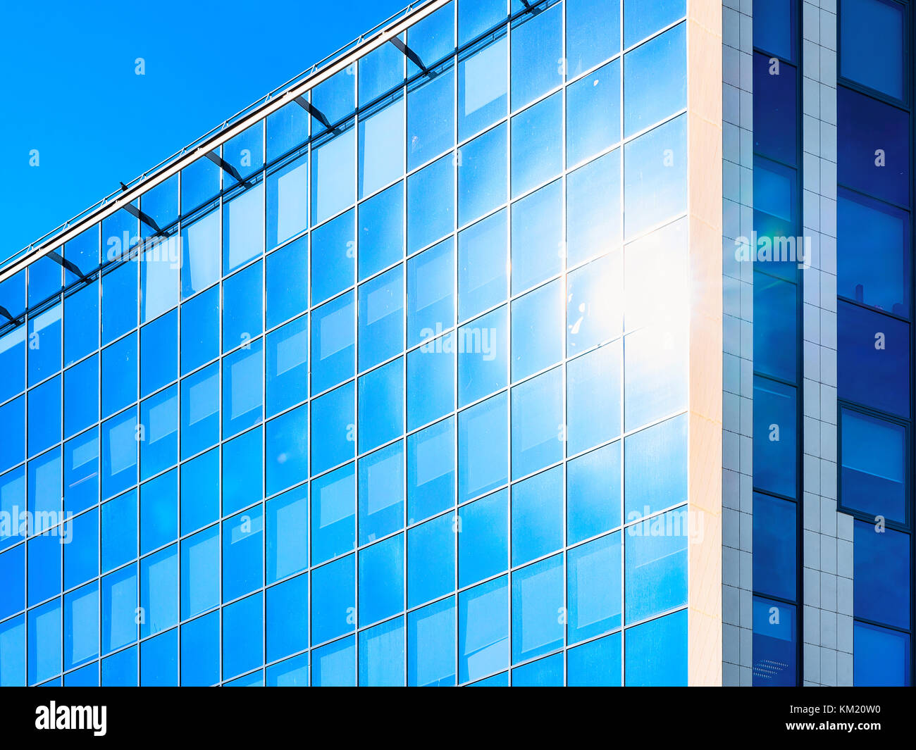 Glass windows reflecting the blue sky as detail of modern architecture ...