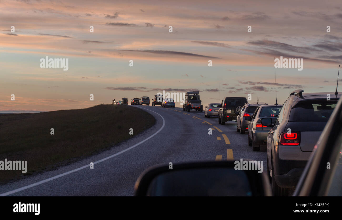 A column of cars on a winding road on the background of mountains and ...