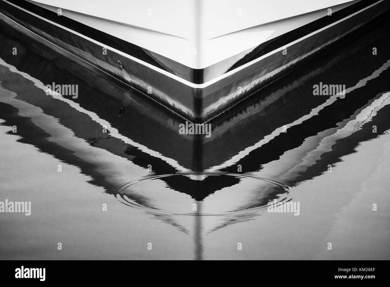 Ripples from a water drop mar the reflection of a yacht's bow on the ...