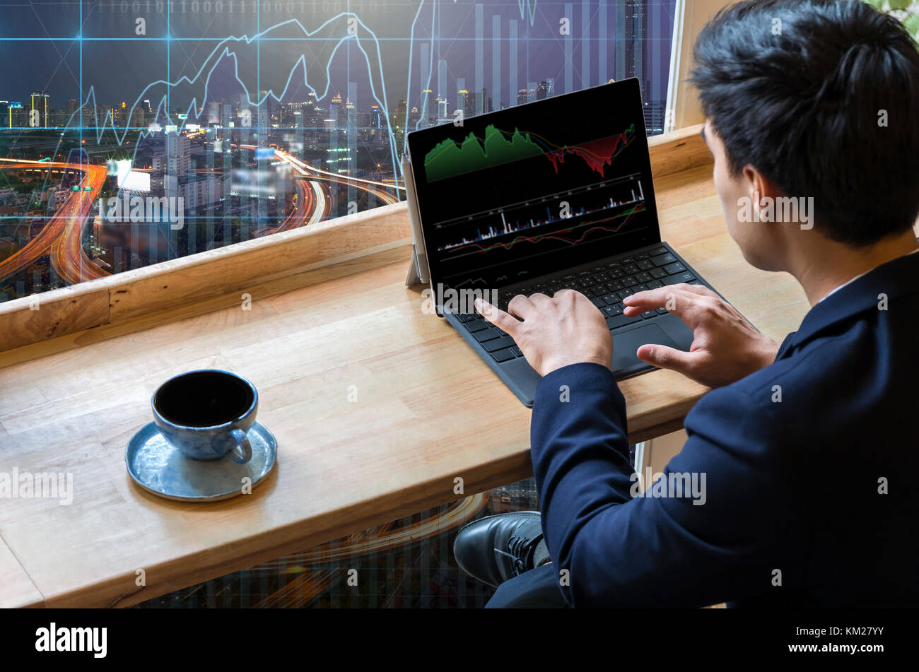 Businessman sitting and using computer laptop showing trading graph ...