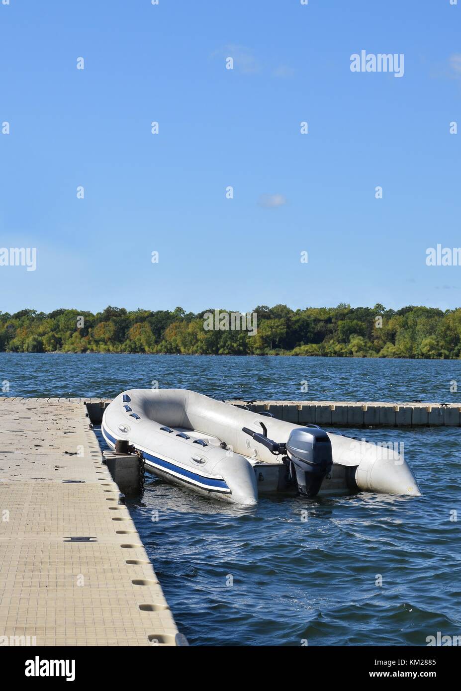 Recreational inflatable white rubber raft with an outboard motor tied ...