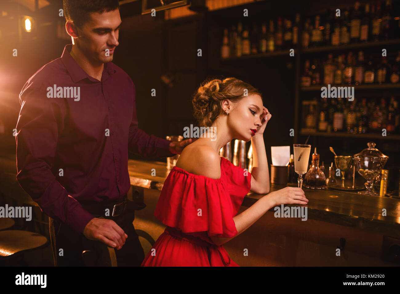 Date in nightclub, attractive couple against bar counter. Woman in red ...