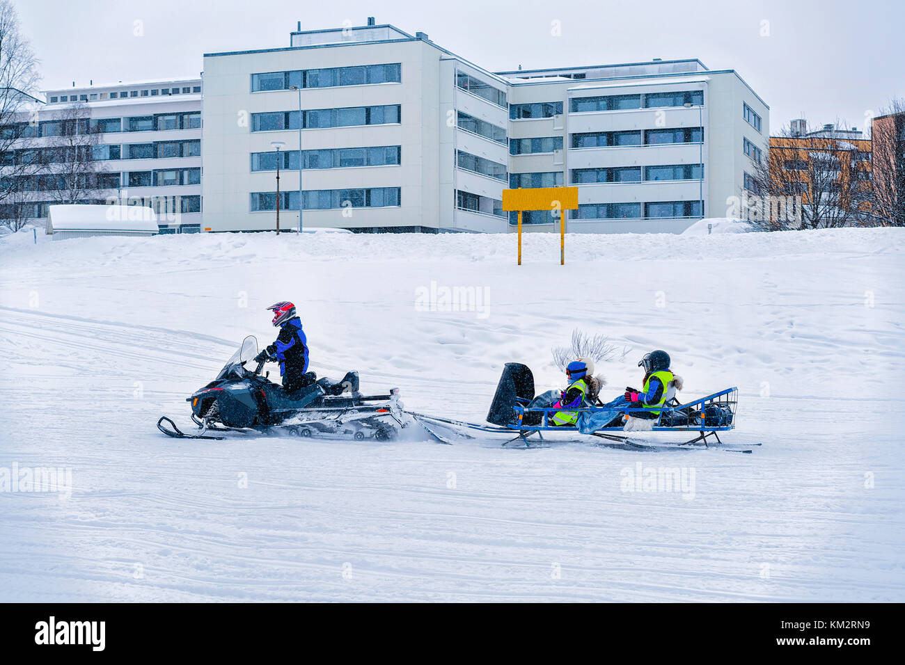 Man riding a snowmobile and children in carriage on the frozen lake in ... Man riding a snowmobile and children in carriage on the frozen lake in ...