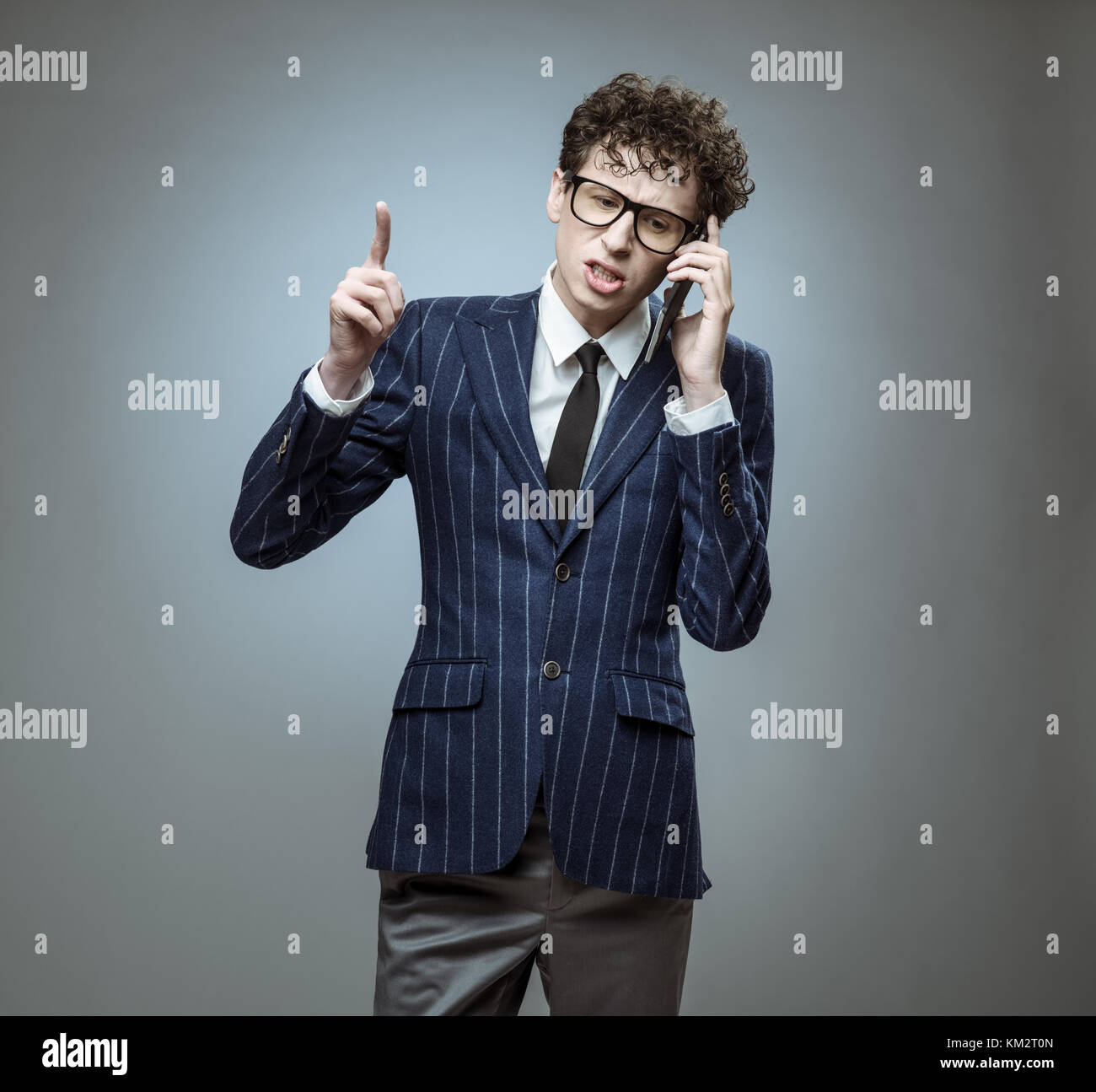 Young man calling on phone with finger up on gray background Stock ...