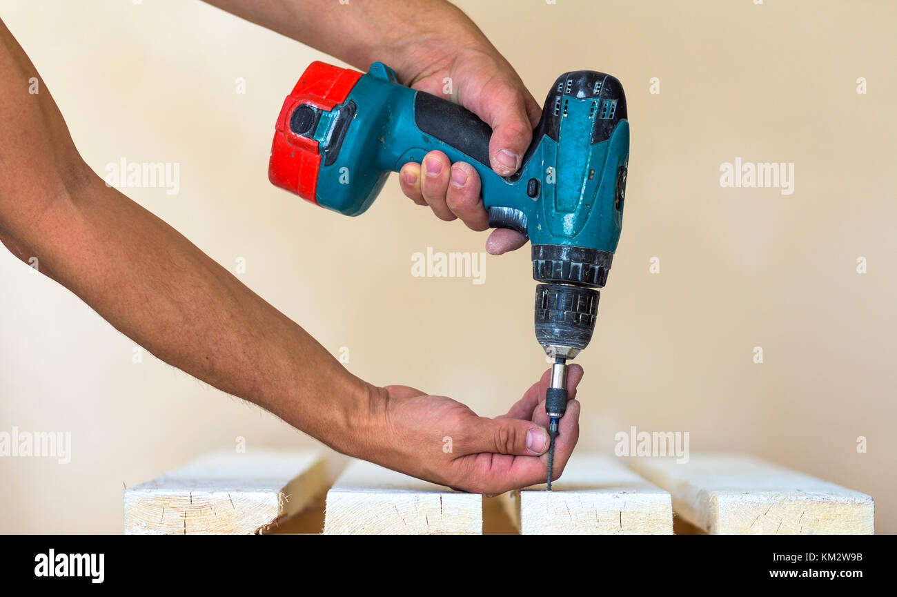 Hand of a worker screws a screw in a wooden board with a cordless ...