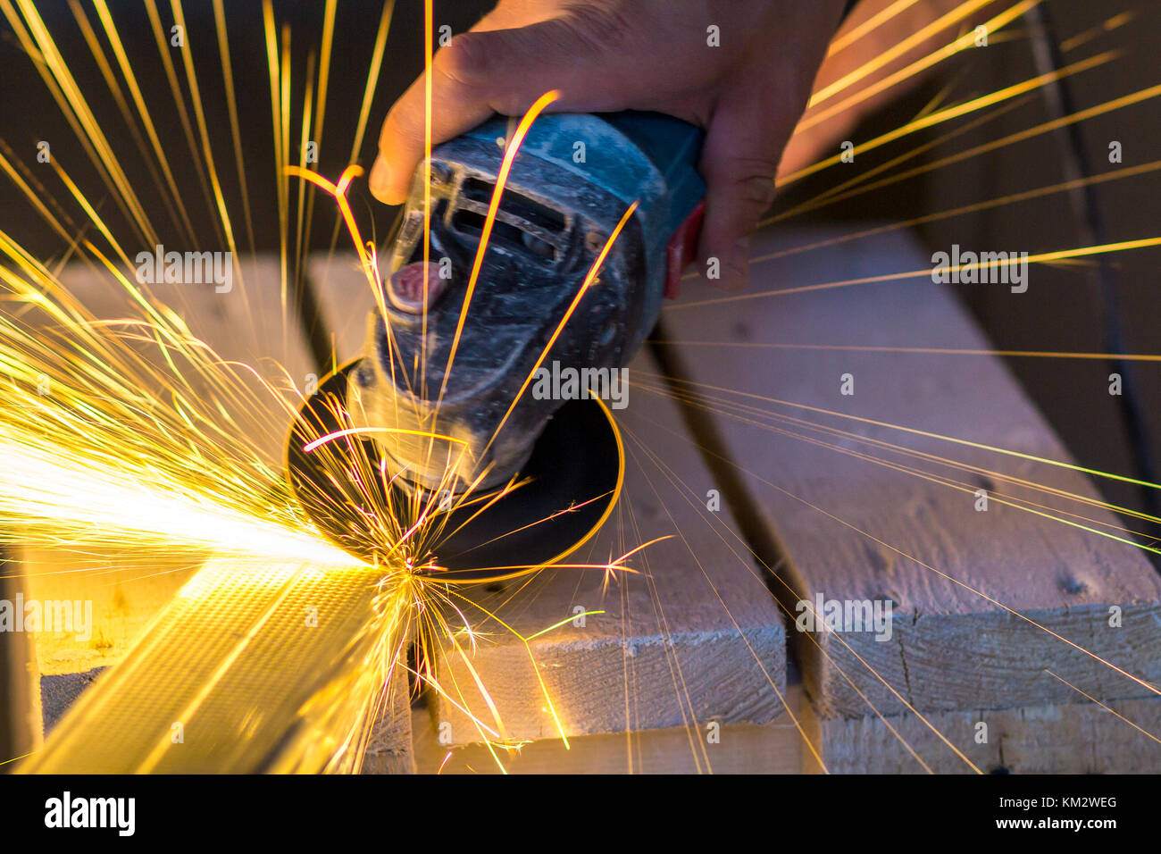 Close-up of worker hands cutting metal with grinder. Sparks while ...