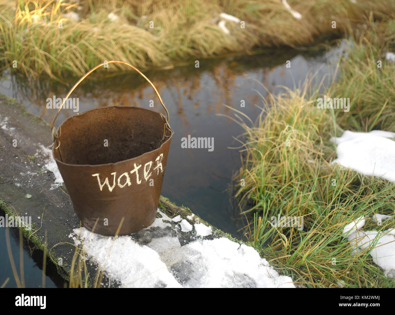 Abandoned rusty bucket with w word Water standing on the bridge across ...