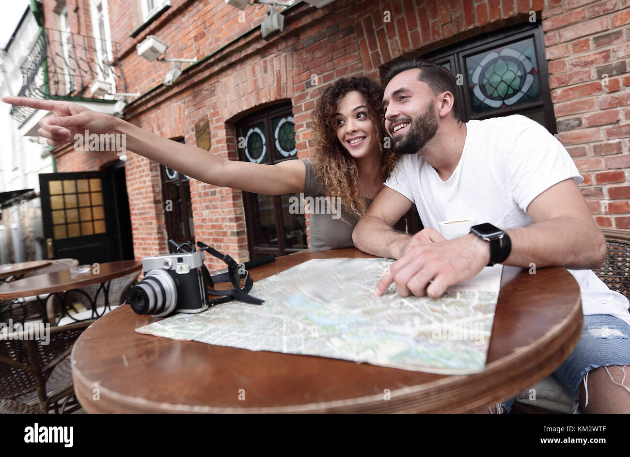 Young tourists drinking coffee at cafe and reading city map Stock Photo ...