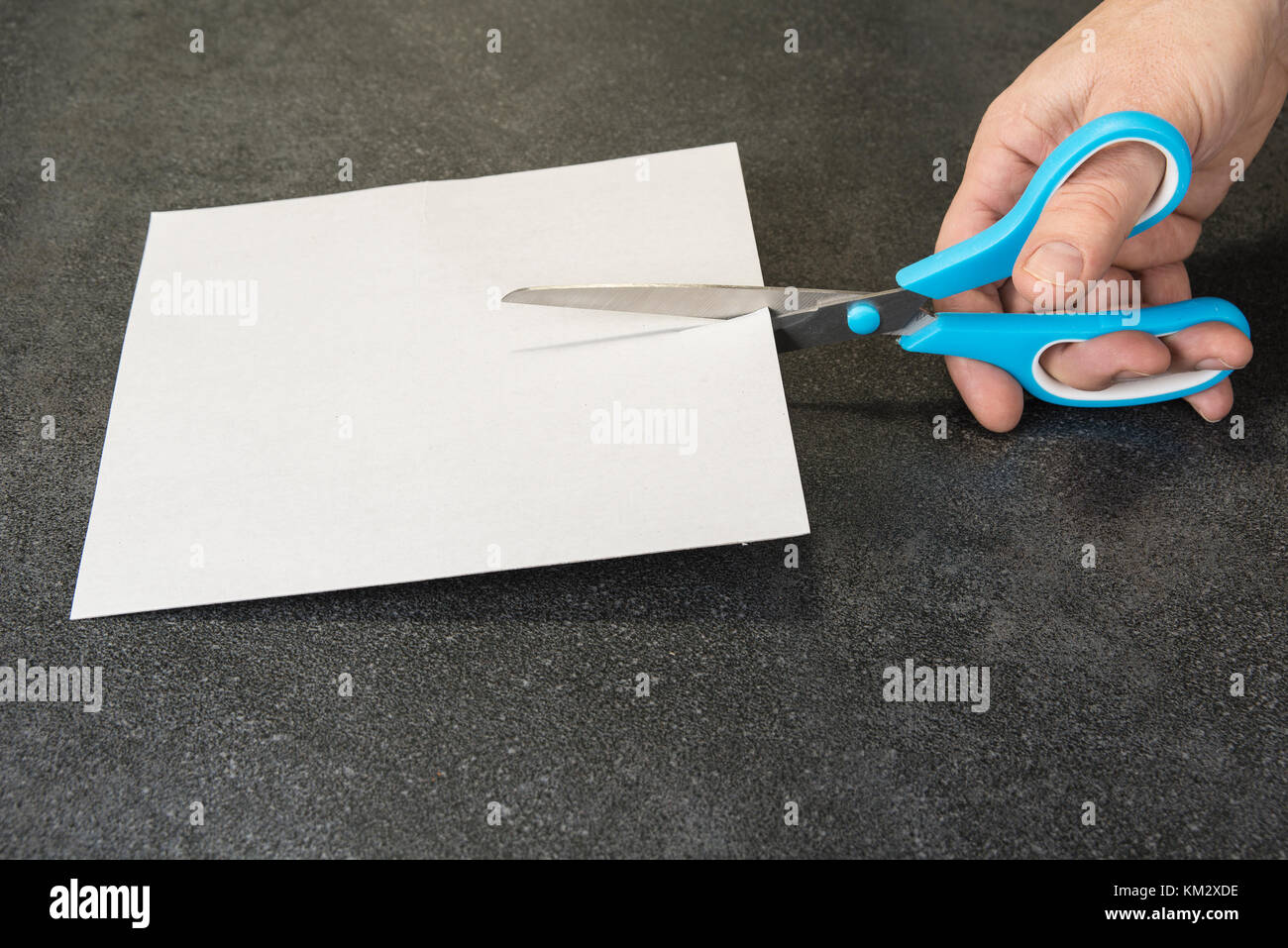 Hand with scissors is cutting the paper Stock Photo - Alamy
