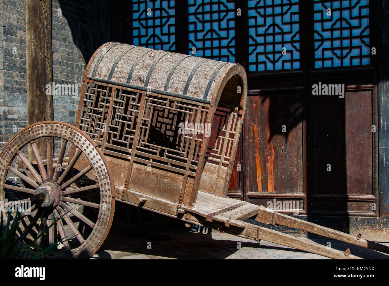 An ancient, antique covered, pull cart parked in front of a preserved ...