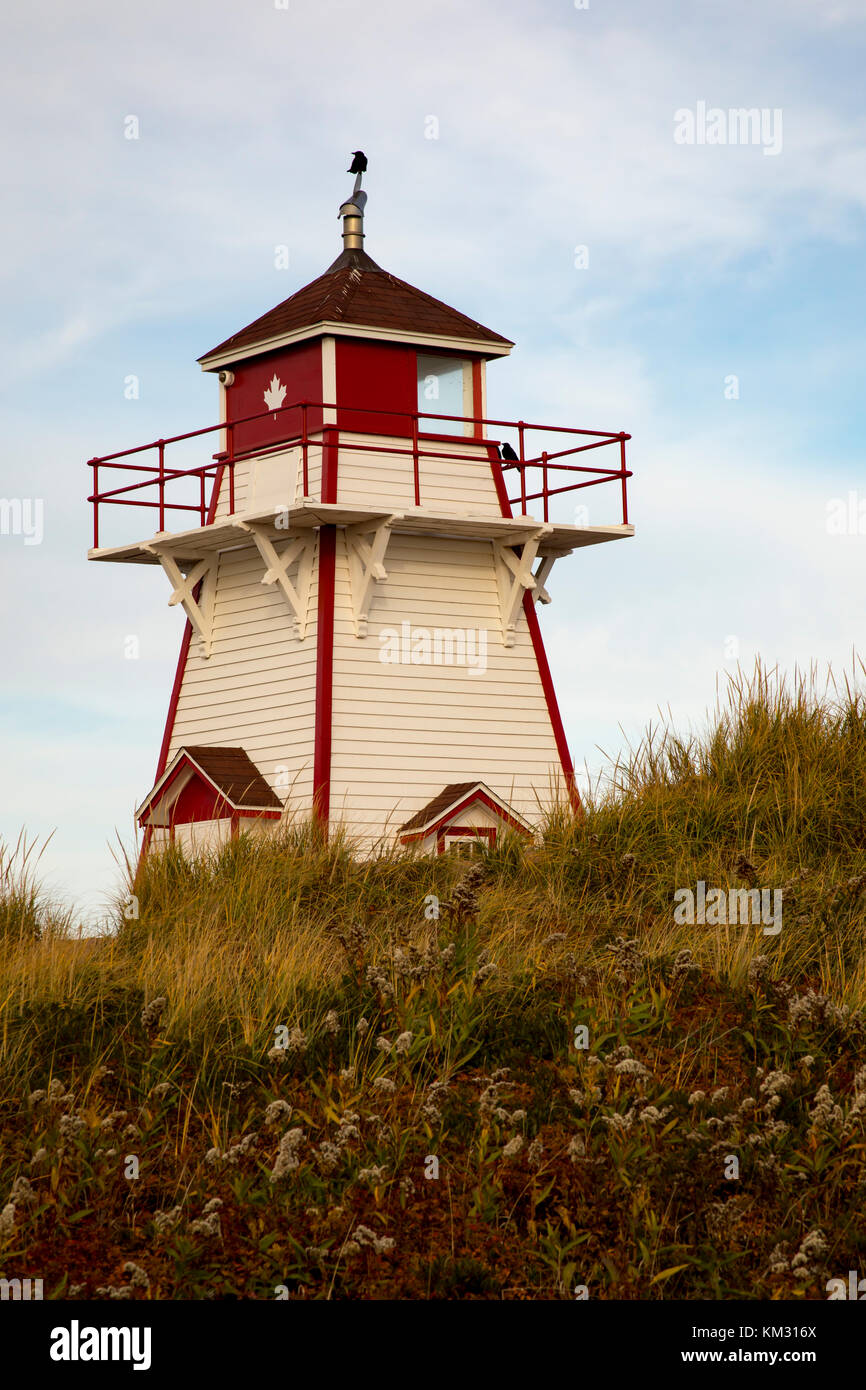 Wooden landmark lighthouse wiith Canadian maple leaf on red along coast ...