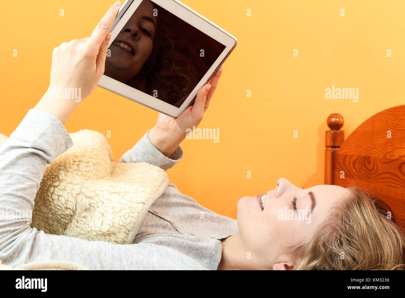 Lazy young woman using computer tablet browsing internet. Girl laying ...