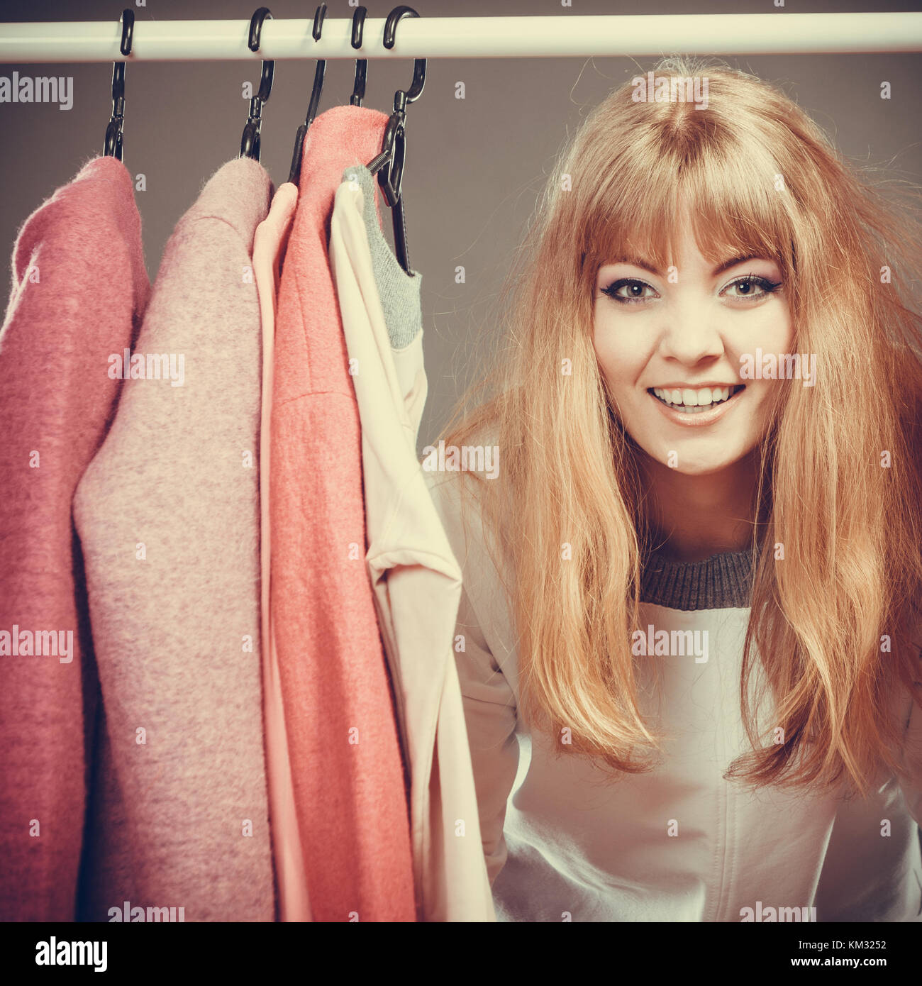 Pretty happy woman between clothing from wardrobe. Young undecided ...