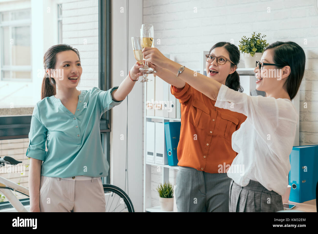 We did it! Cheerful young people looking excited while clink champagne together sitting at the ...