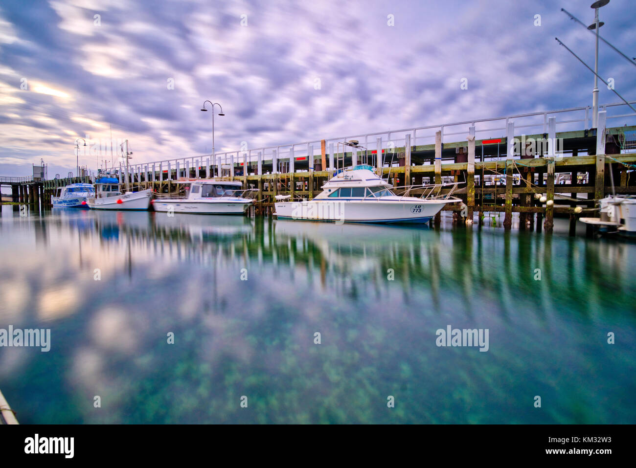 Small fishing boats docked at jetty Stock Photo - Alamy