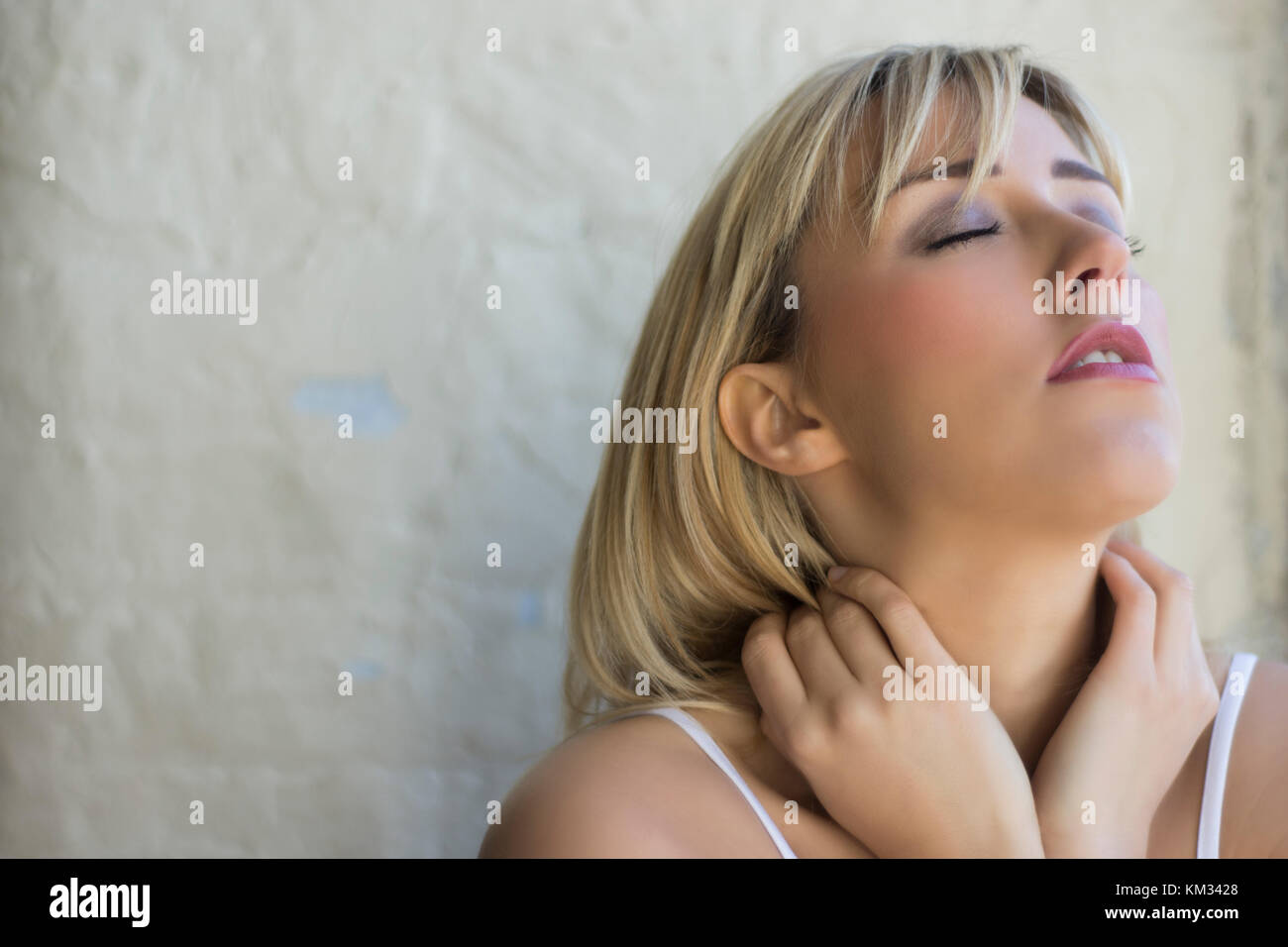 Tired blond woman hands touching neck Stock Photo - Alamy