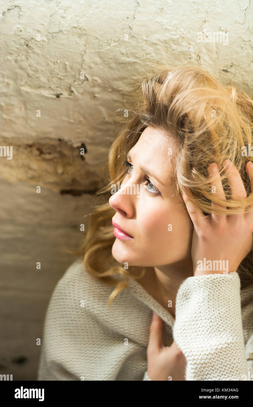 Scared young blond woman hand on head looking up Stock Photo - Alamy