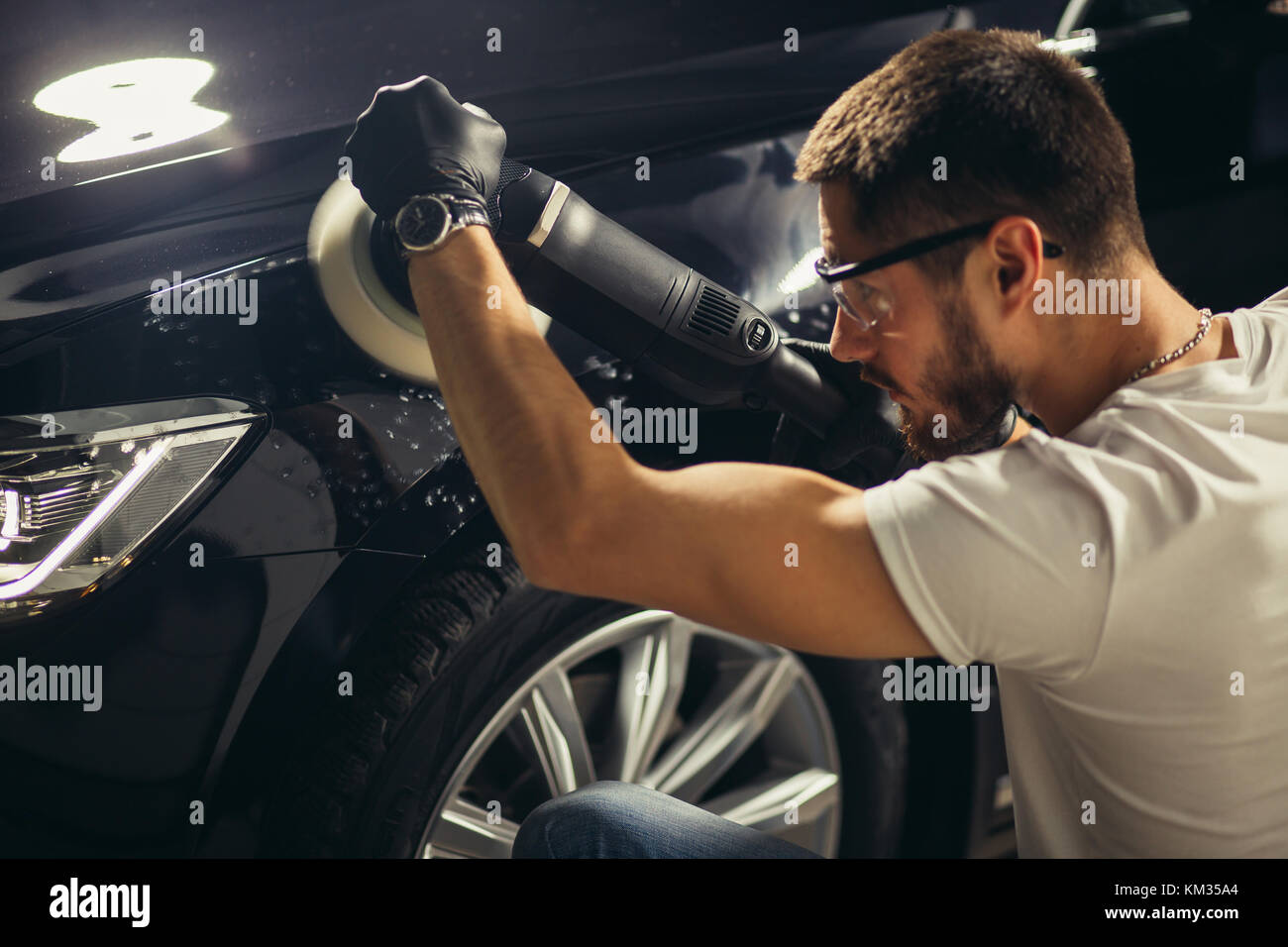 Car detailing - man with orbital polisher in auto repair shop ...