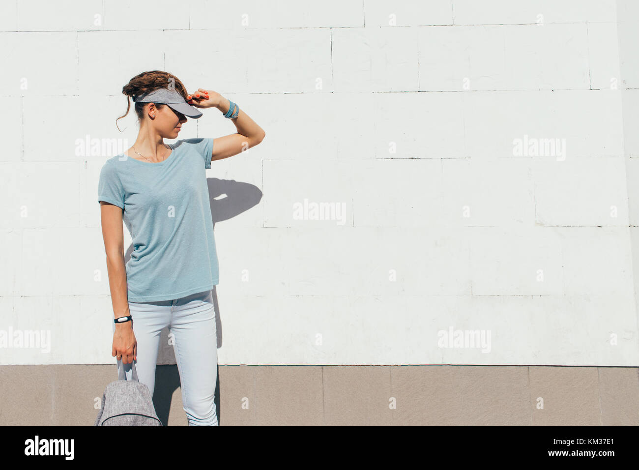 Young stylish girl in a cap on a white wall background, copy space ...