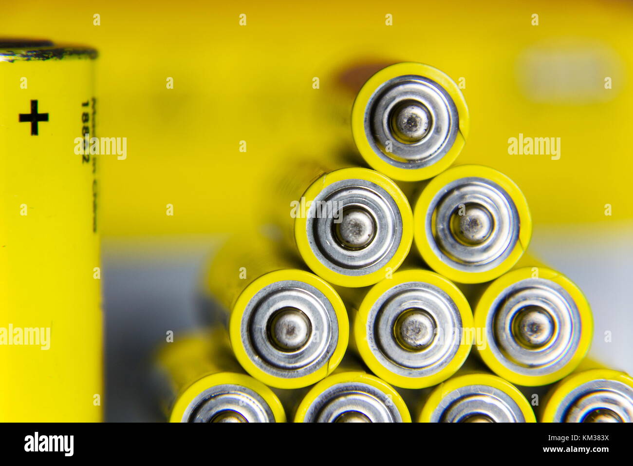 Stack of yellow AA batteries close up abstract coloured background ...