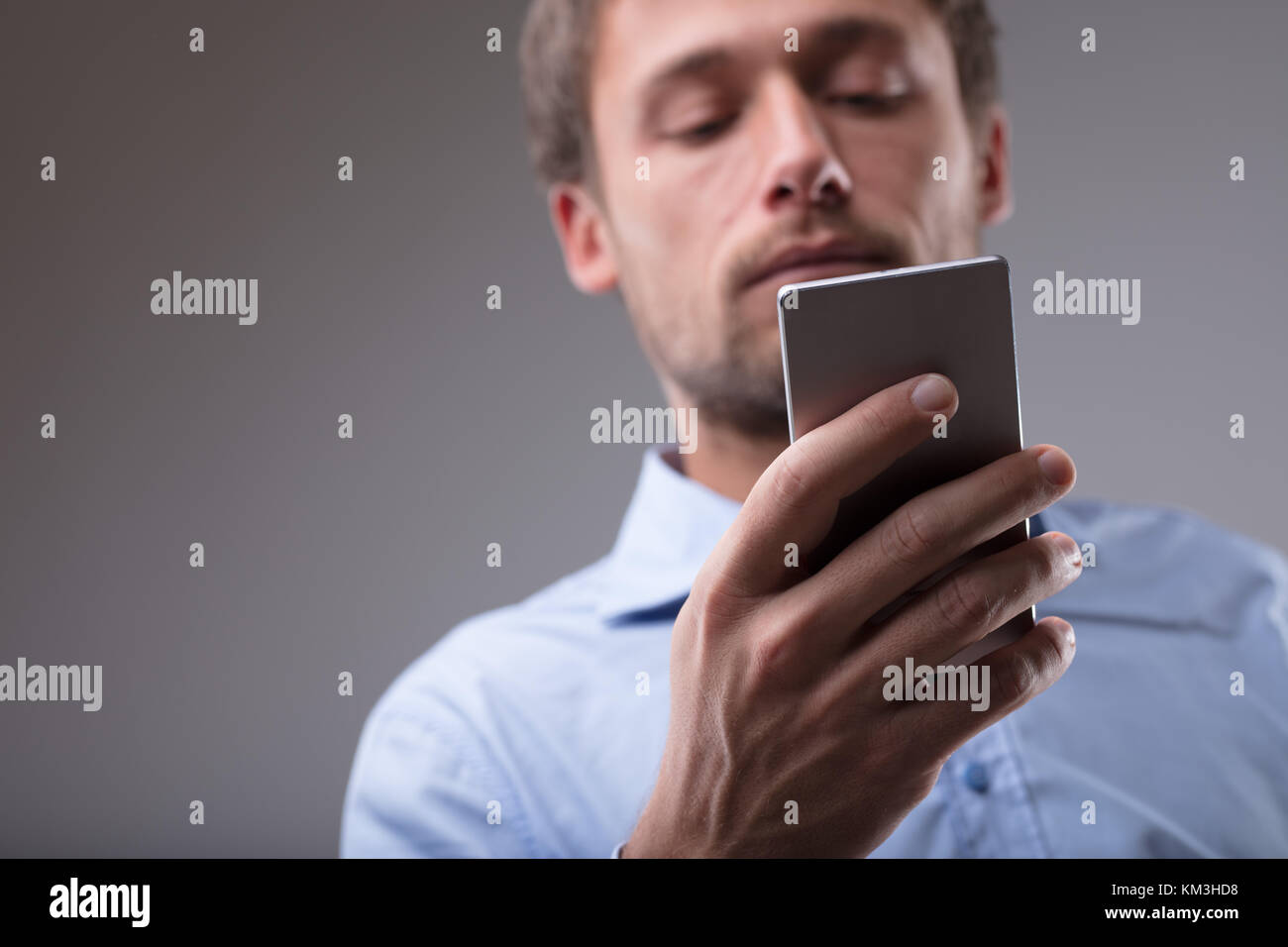 Man reading a message on his mobile phone in a low angle view with ...
