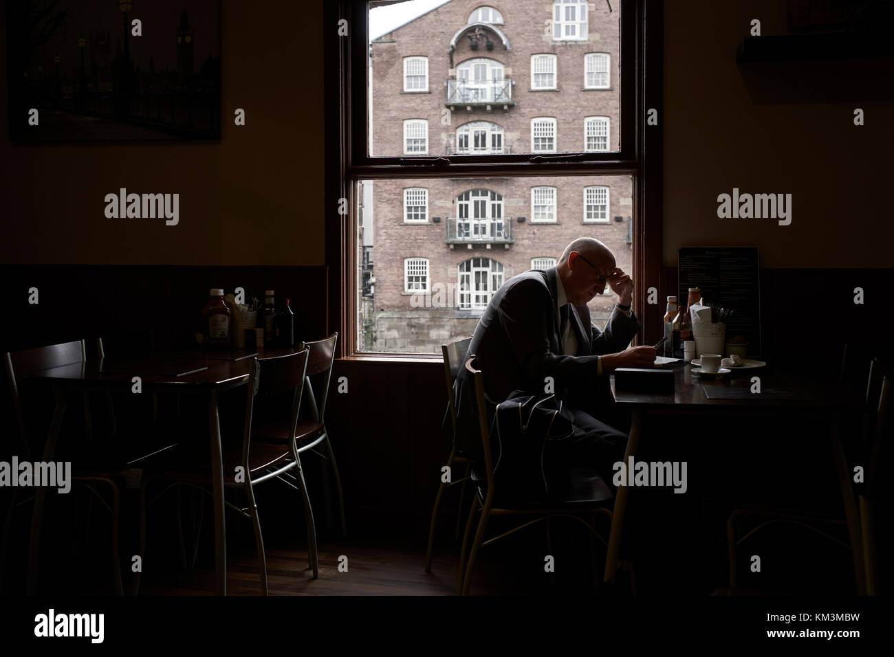 Business man sitting at a cafe working backlit Stock Photo - Alamy