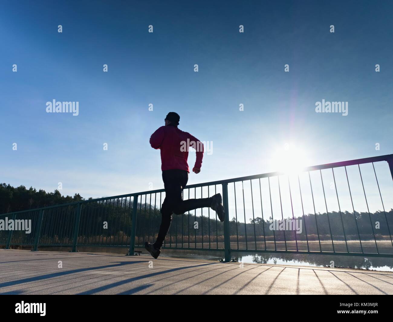 Rear view to runner in blue t-shirt and black leggings running on ...