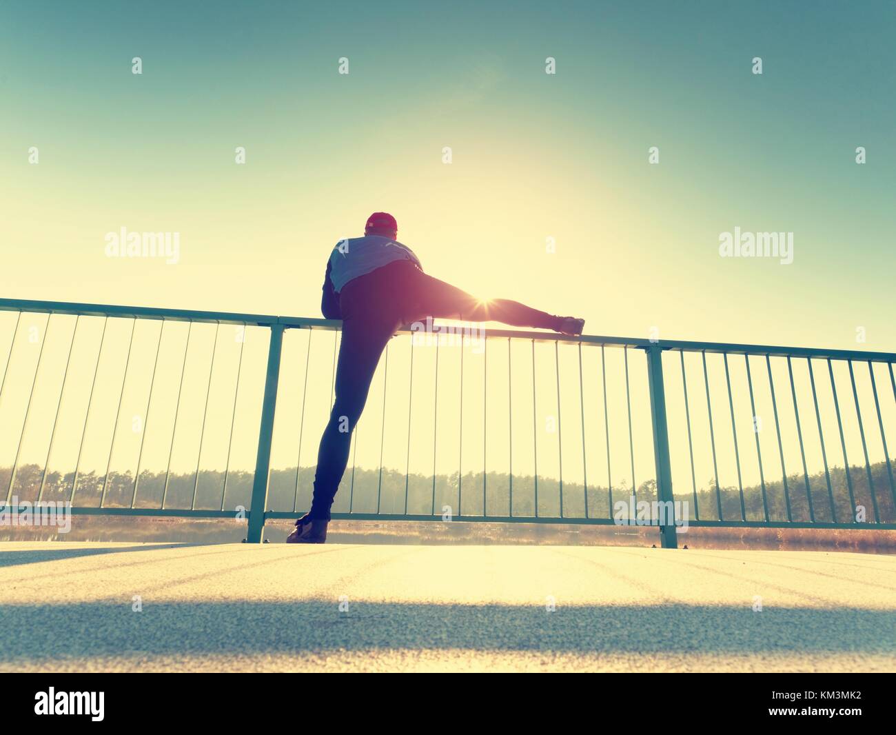 Morning runner in tall black leggings makes body stretching on bridge ...
