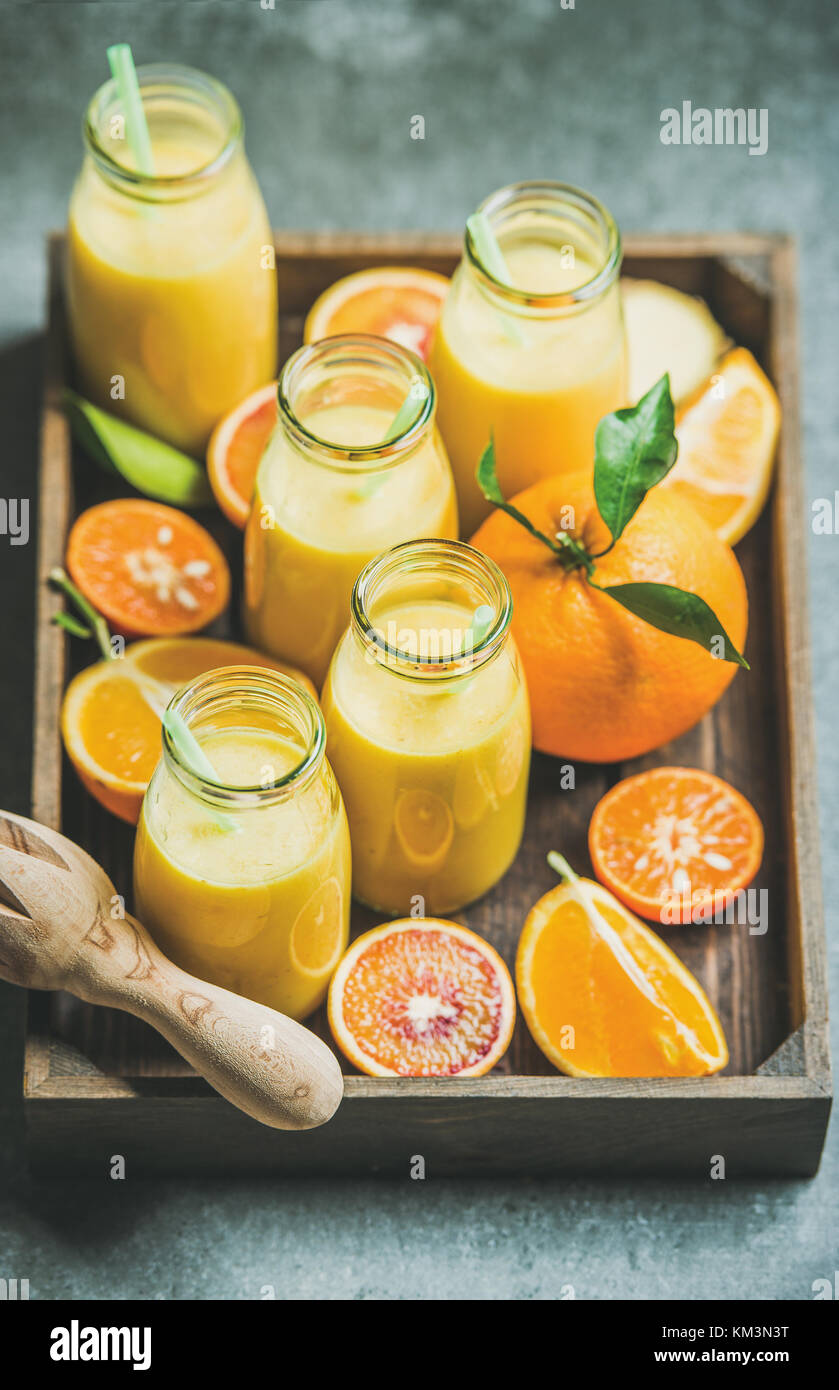 Healthy yellow smoothie with citrus fruit and ginger in bottles in ...