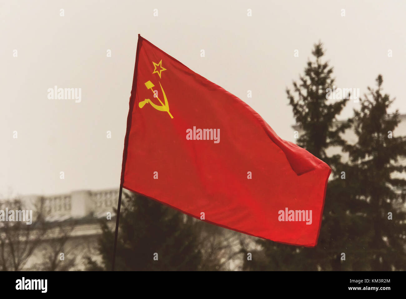 Old shabby red flag of the USSR on the flagstaff. The flag depicts a ...