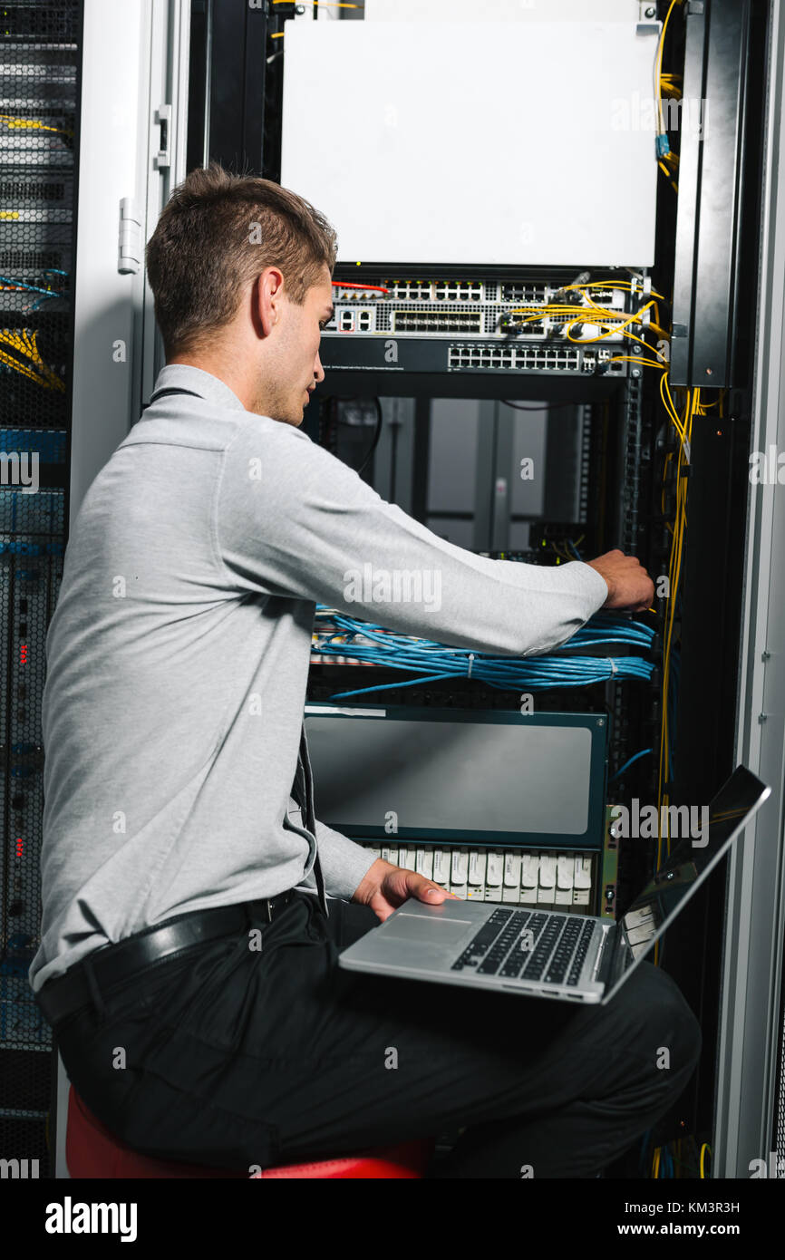Young man is standing next to the racks with computer equipment Stock ...