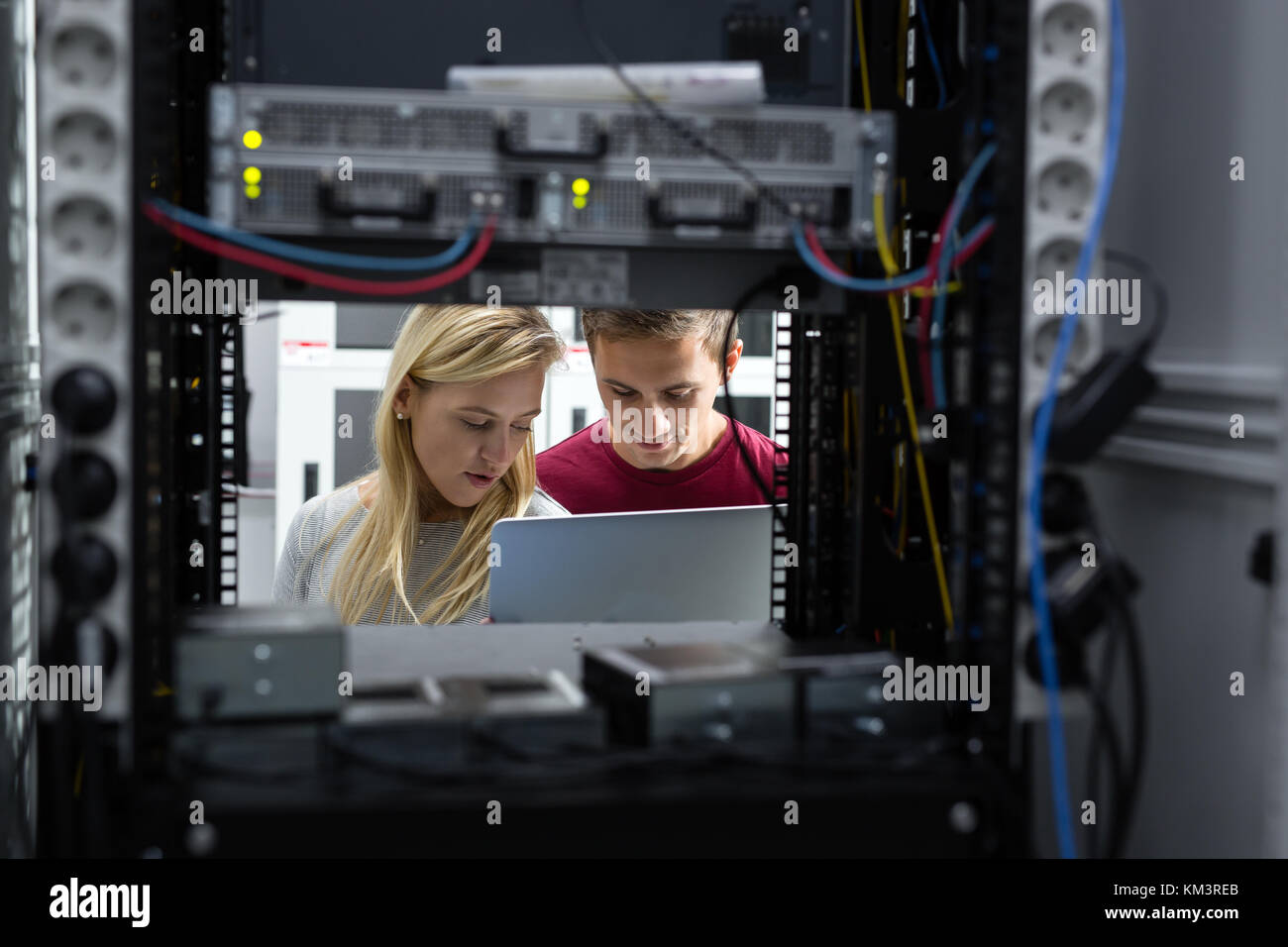 Team of technicians working together on servers at the data centre ...