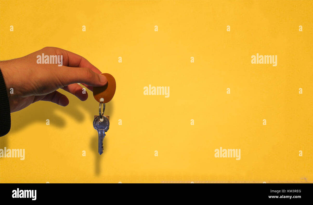 hand holding keys after a successful property sale on a yellow ...