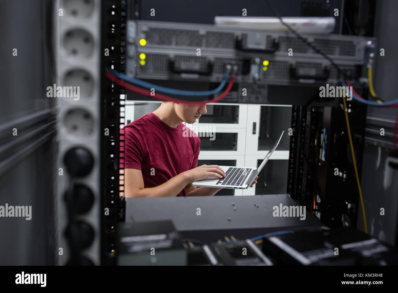 Portrait of modern young man holding laptop standing in server room ...