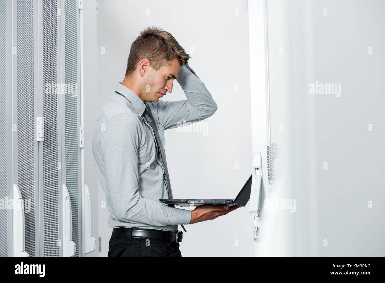 Portrait of modern young man holding laptop standing in server room ...
