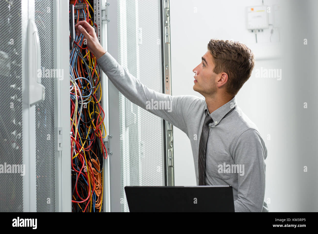 Portrait of modern young man holding laptop standing in server room ...
