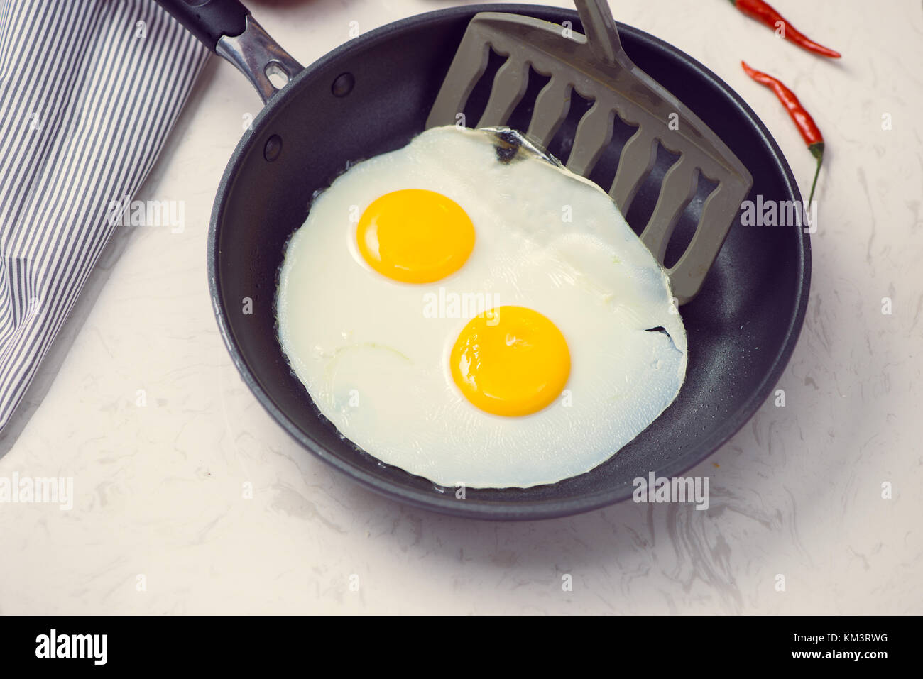 Eating in the process, fried eggs in a frying pan for breakfast on a ...