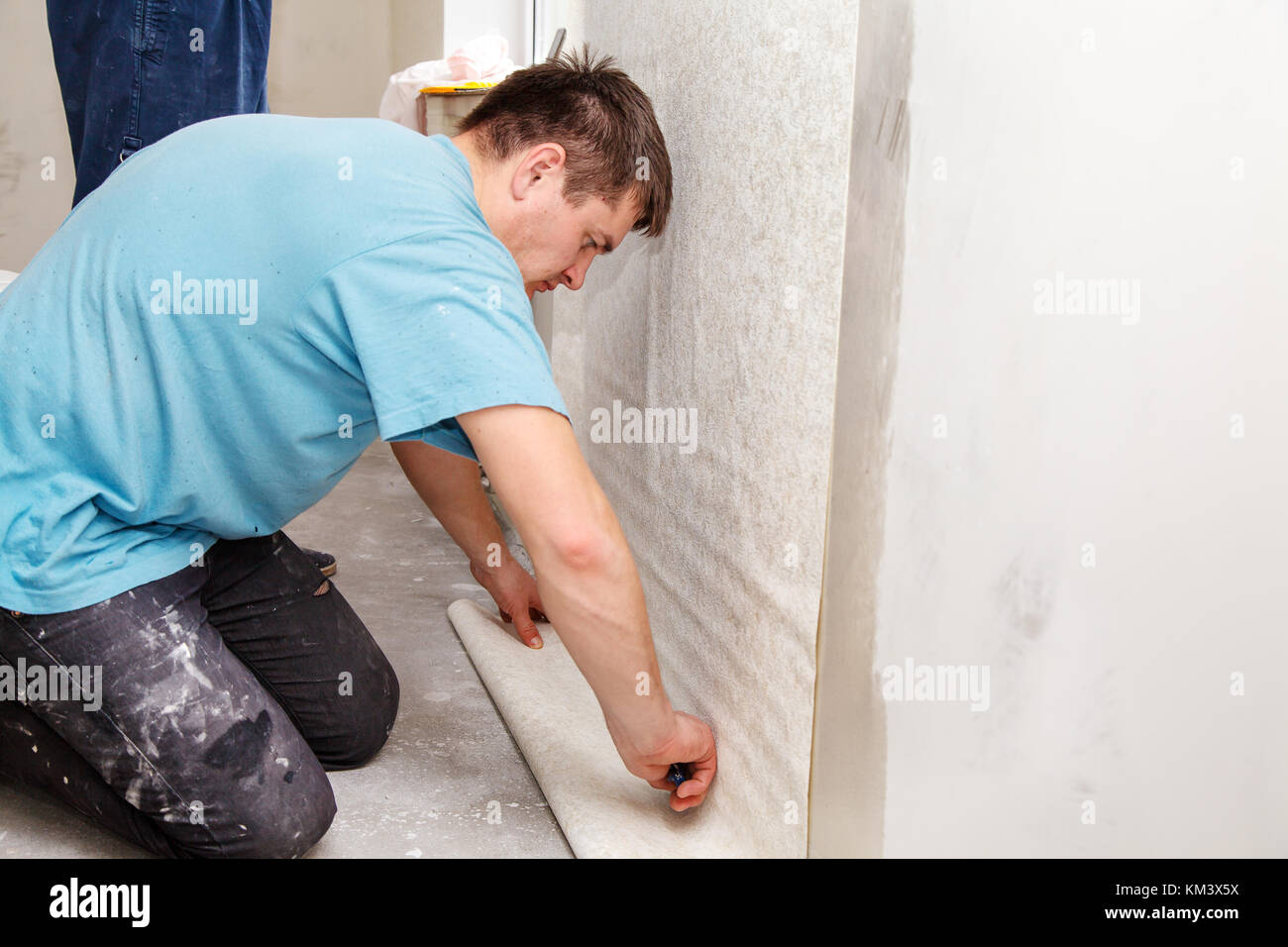 young worker smoothing wallpaper in his house closeup Stock Photo - Alamy
