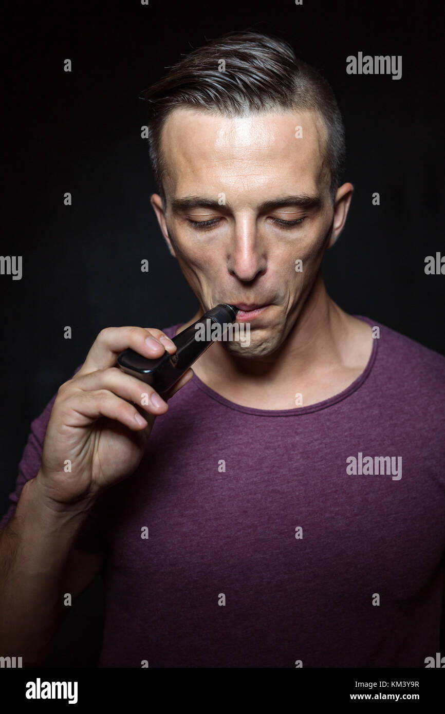 Man on black background vaping and releasing a cloud Stock Photo - Alamy