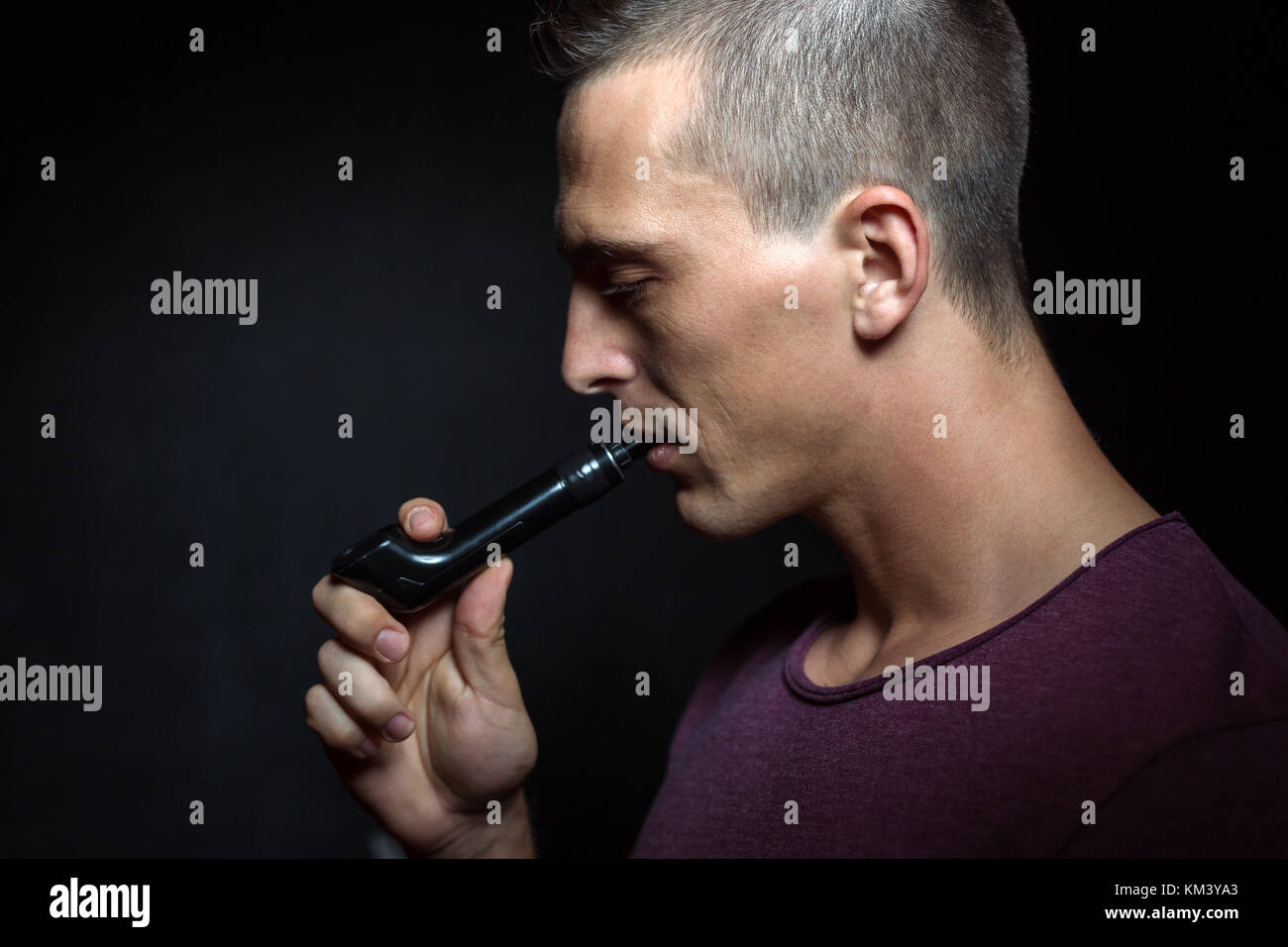 Man on black background vaping and releasing a cloud Stock Photo - Alamy
