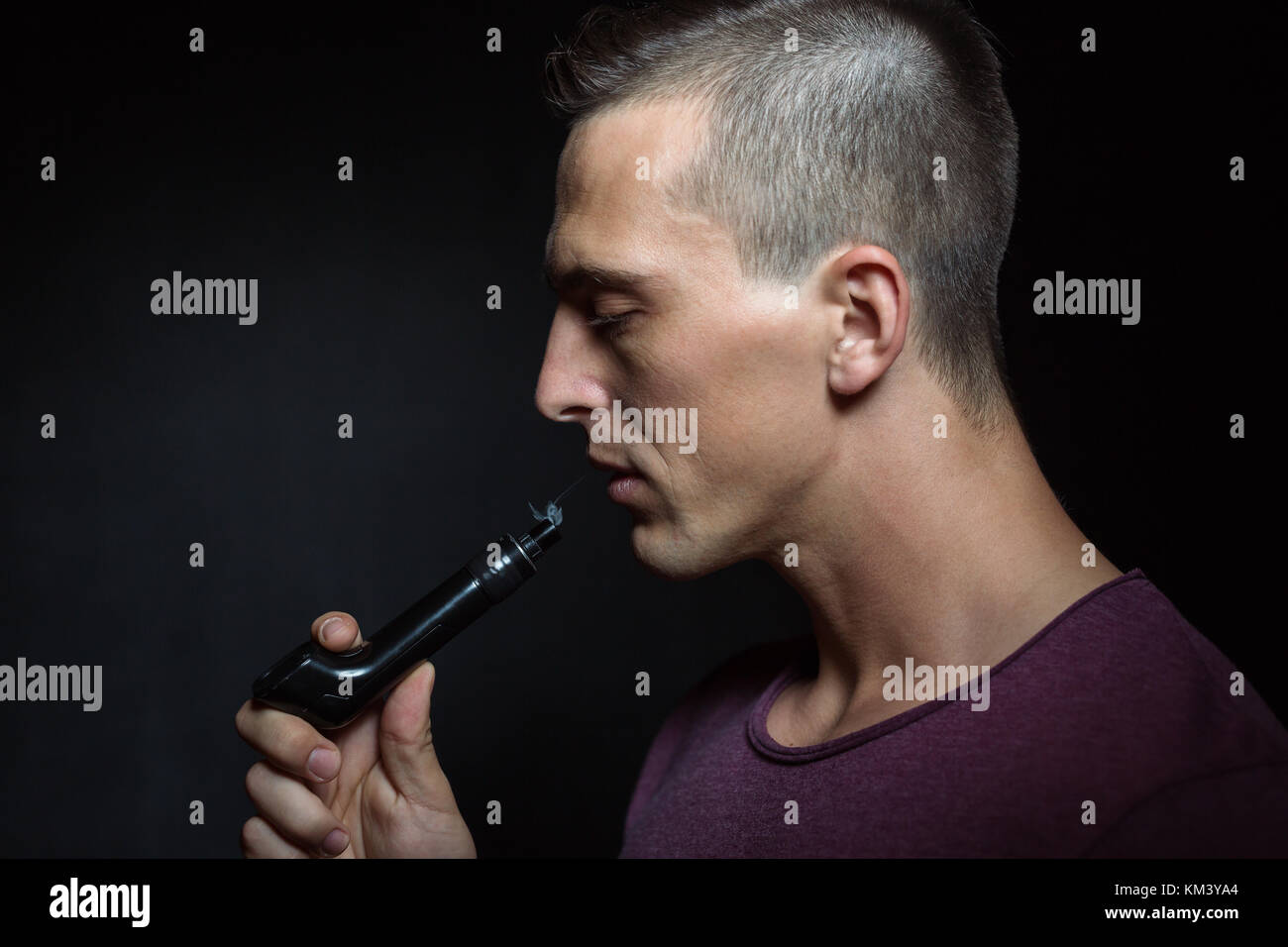 Man on black background vaping and releasing a cloud Stock Photo - Alamy