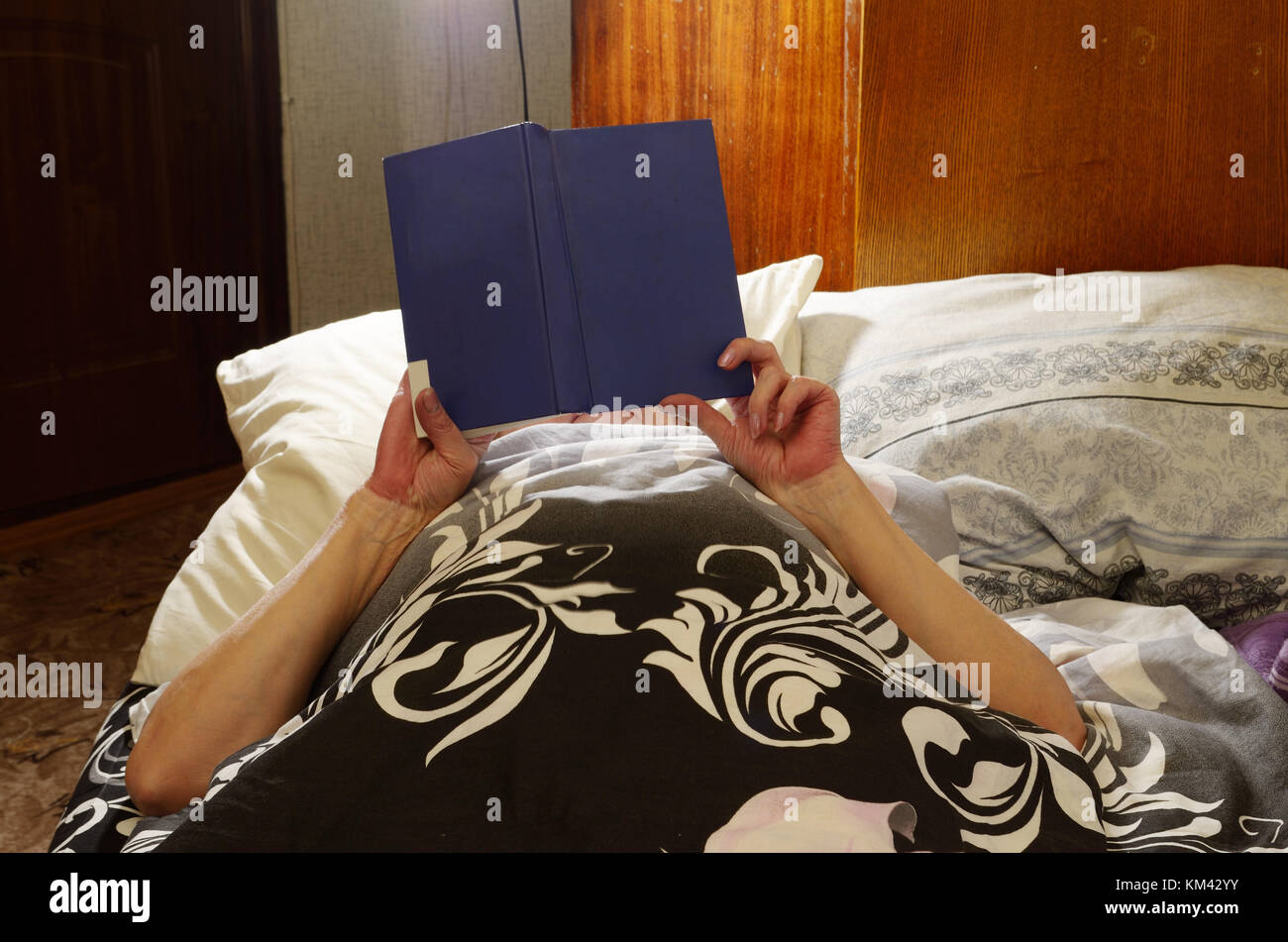 The woman before going to sleep reading a book.It calms the mind Stock ...