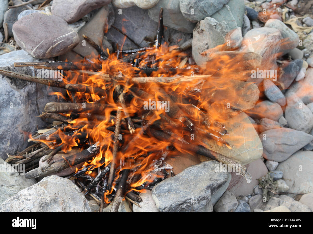 big bonfire made with stones in a circle with a lively flame of fire ...