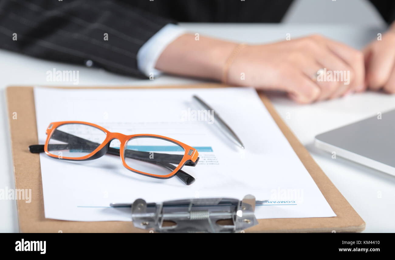 Closeup of white desktop with glasses, notepads, pen and other items ...