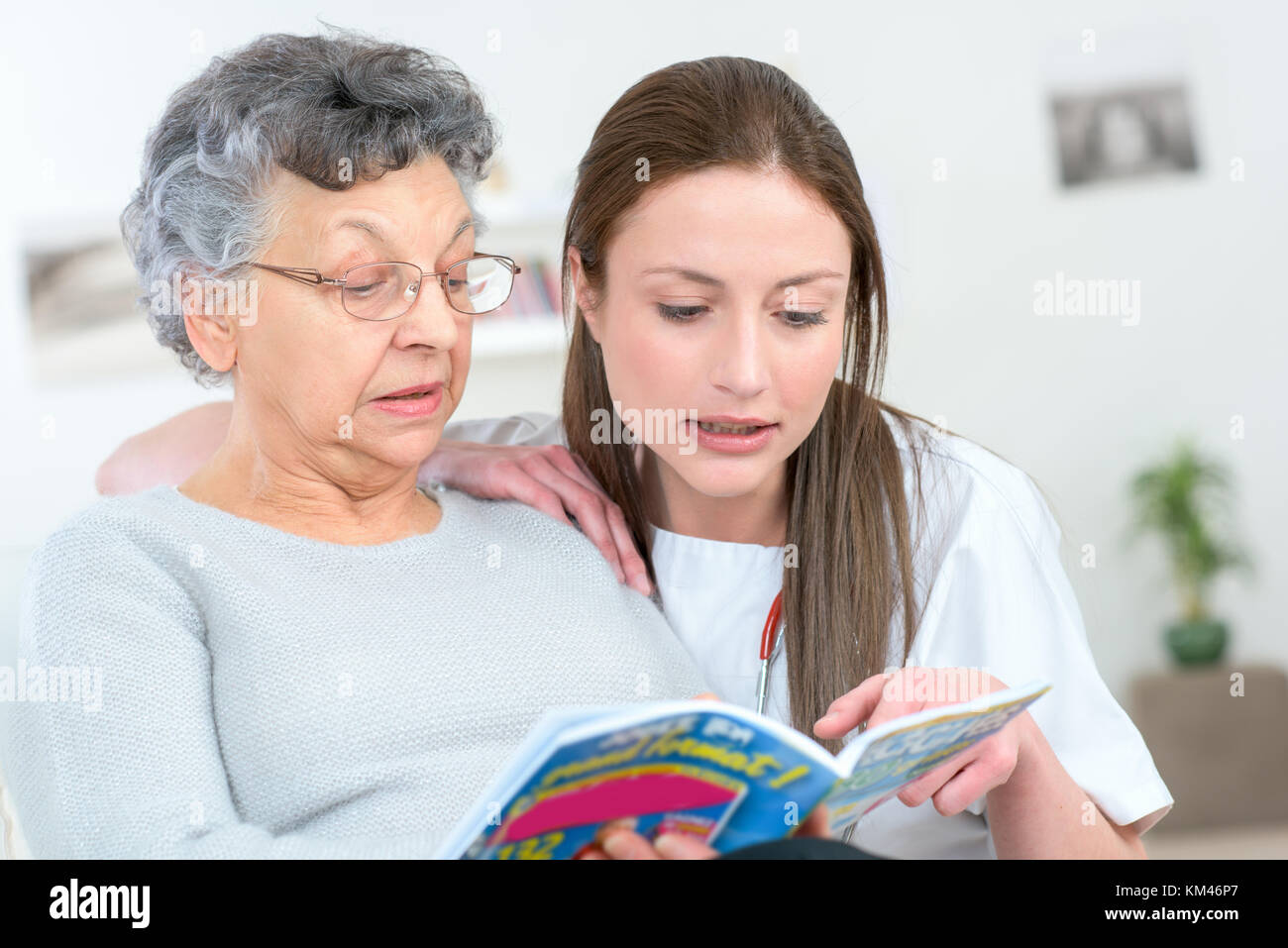 caregiver reading a book with an elderly patient Stock Photo - Alamy