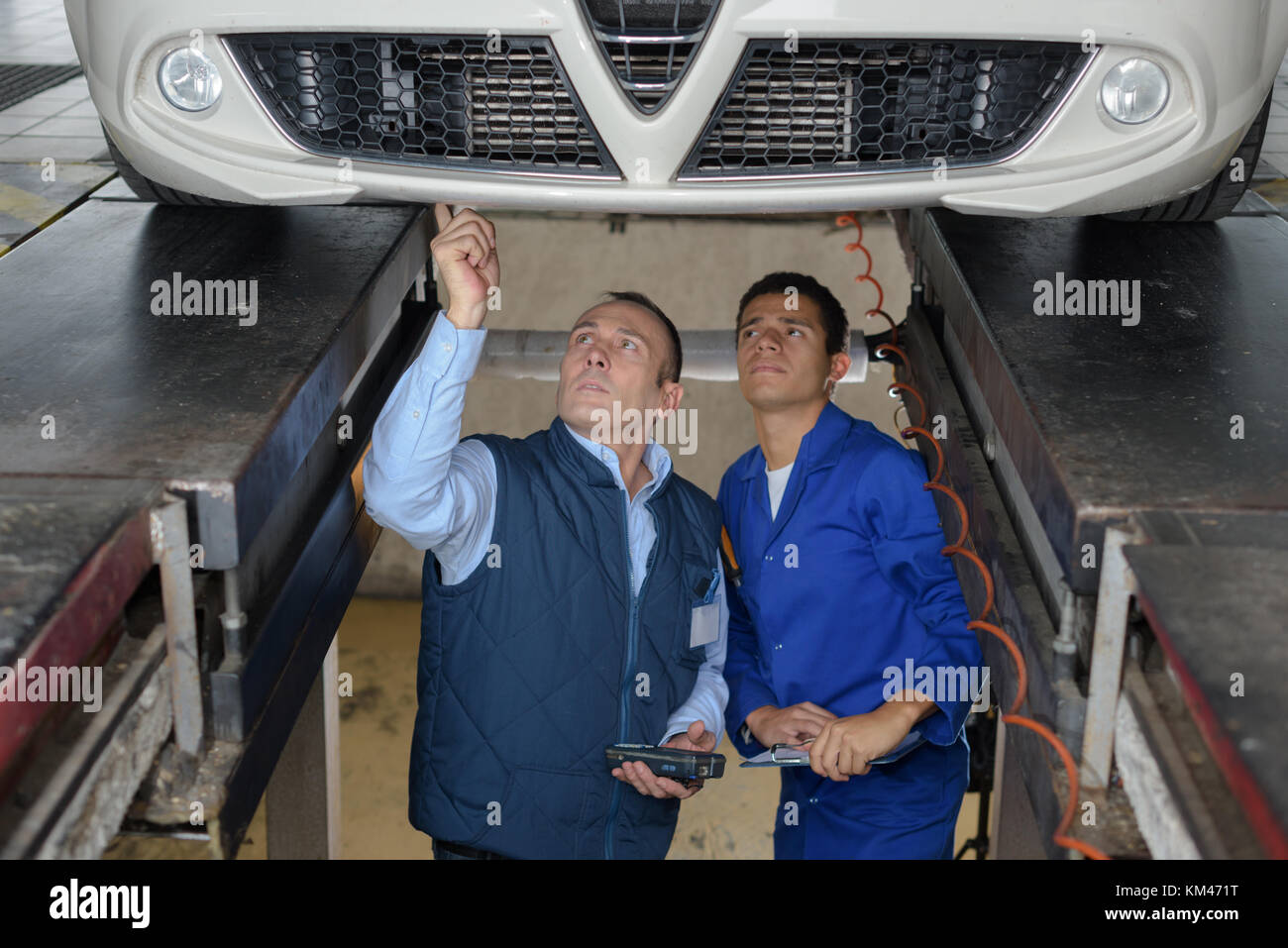 mechanics inspecting a lifted car Stock Photo - Alamy