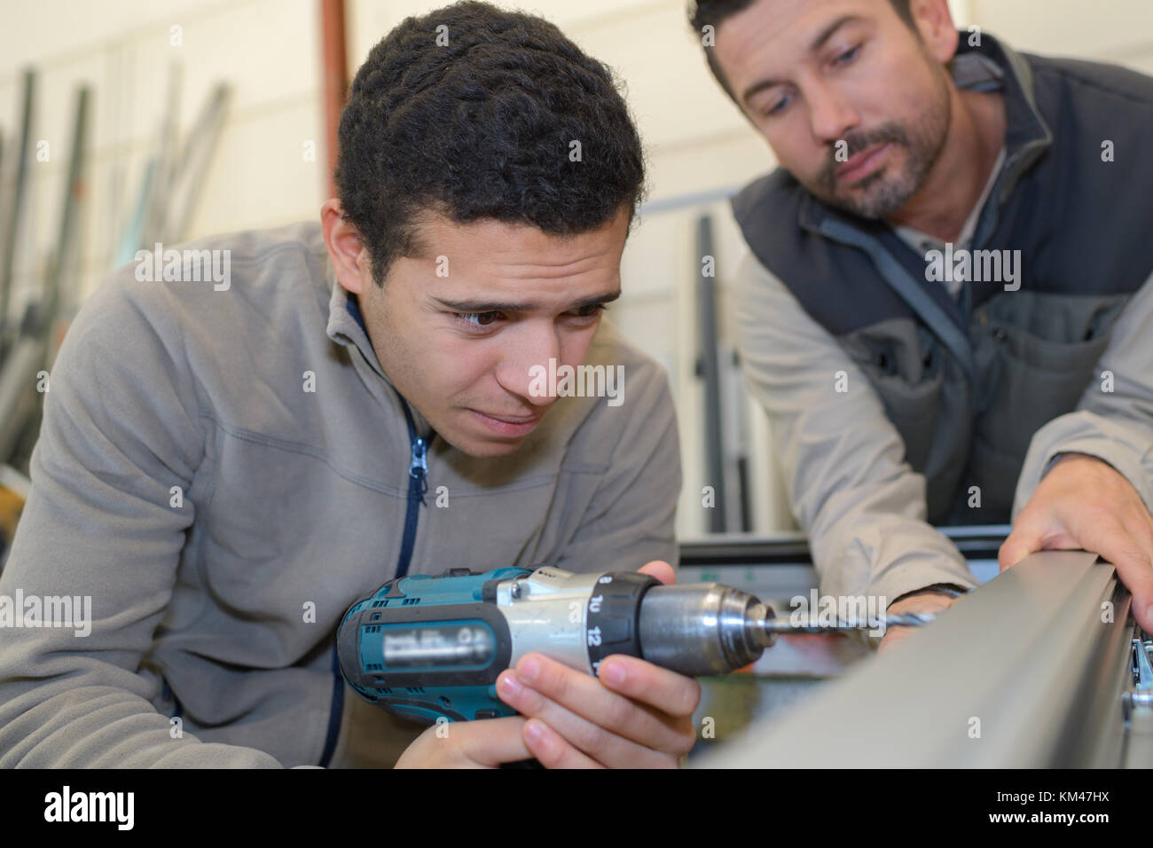 engineer showing apprentice how to use drill in factory Stock Photo - Alamy