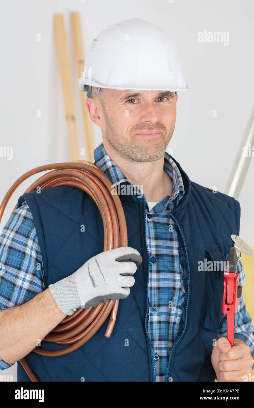 smiling worker carrying corrugated conduit Stock Photo - Alamy